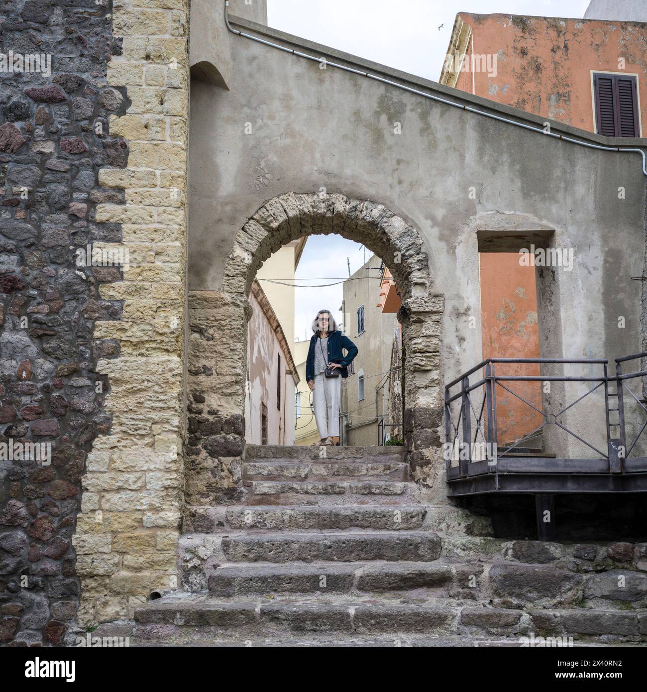 Woman poses on a walkway with architectural detail of walls and steps ...