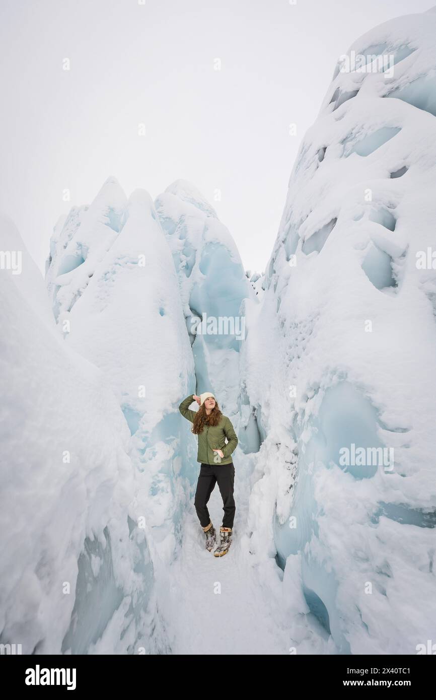 Teenage girl leaning on the Matanuska Glacier in the middle of blue ice ...