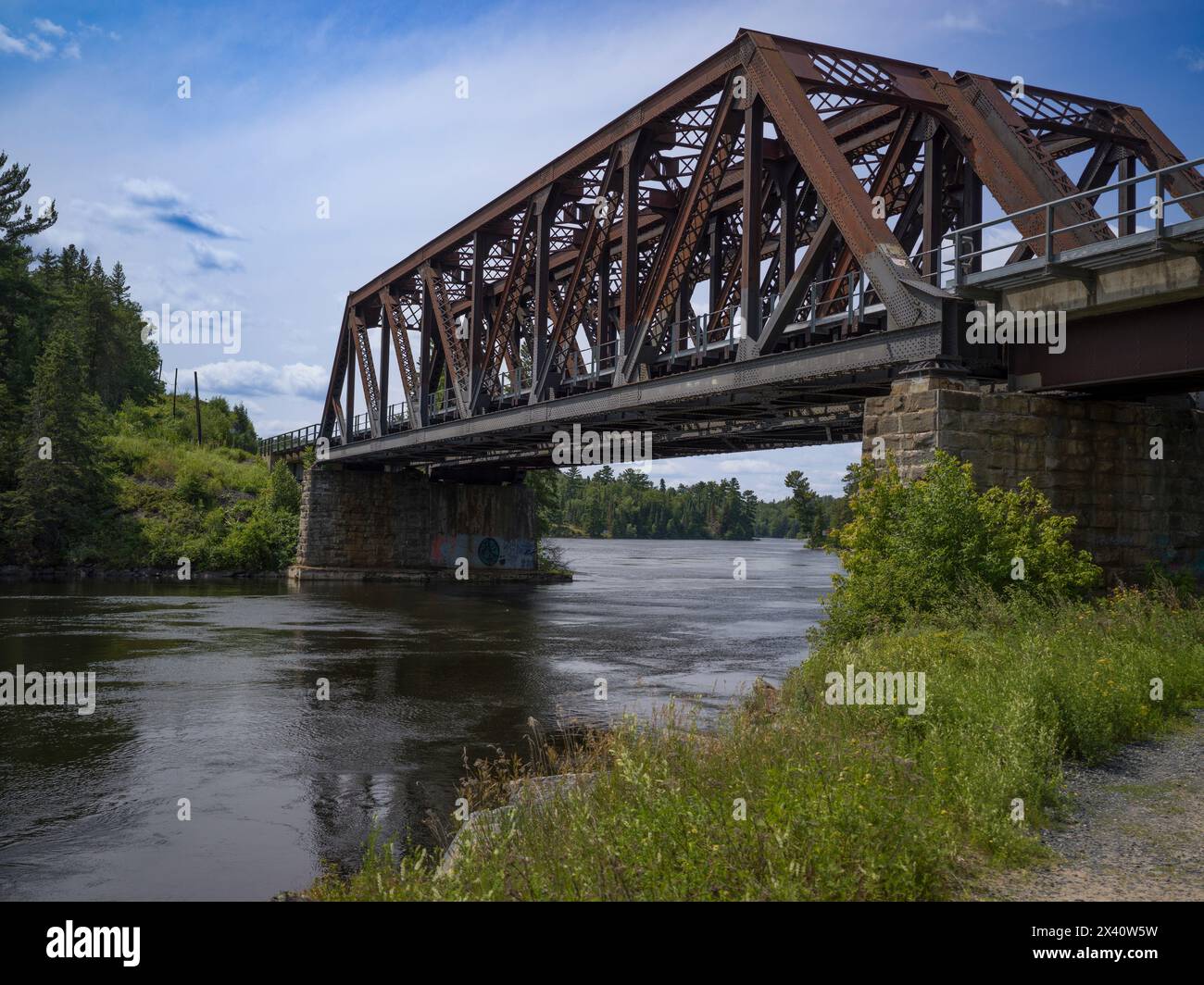 Railroad bridge crossing over a river with a walking path along the ...