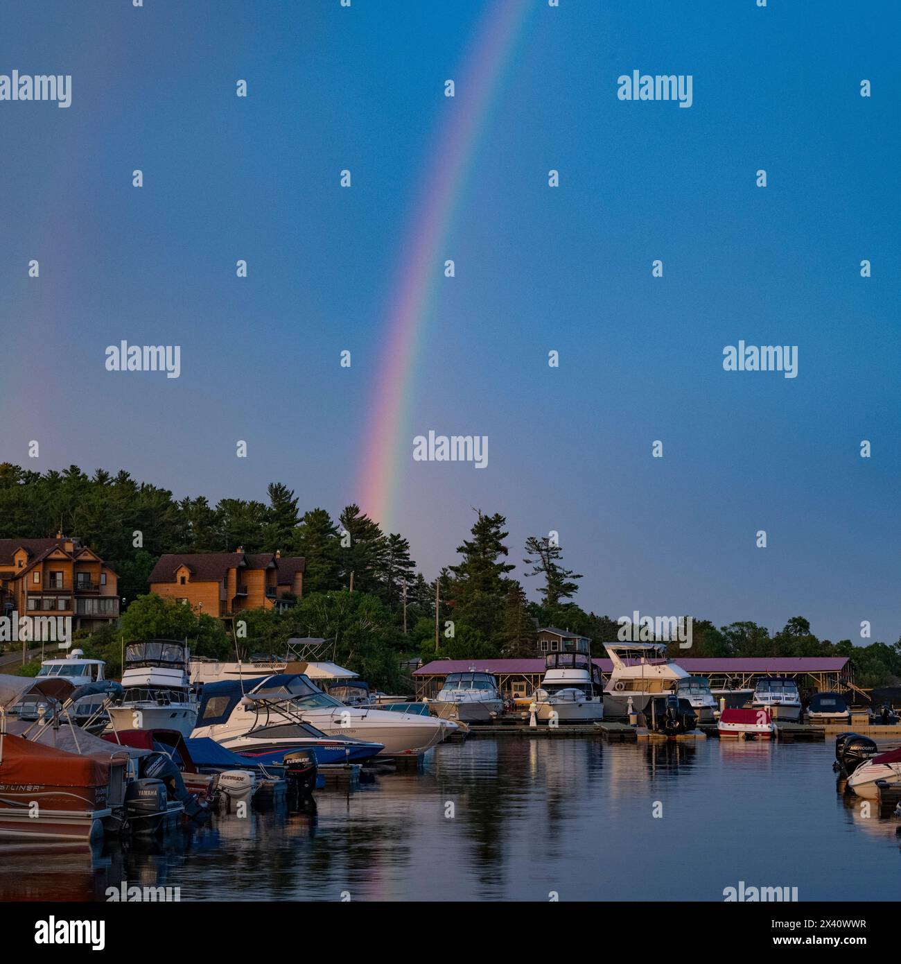 Rainbow stretches over a lake harbour; Lake of the Woods, Ontario ...