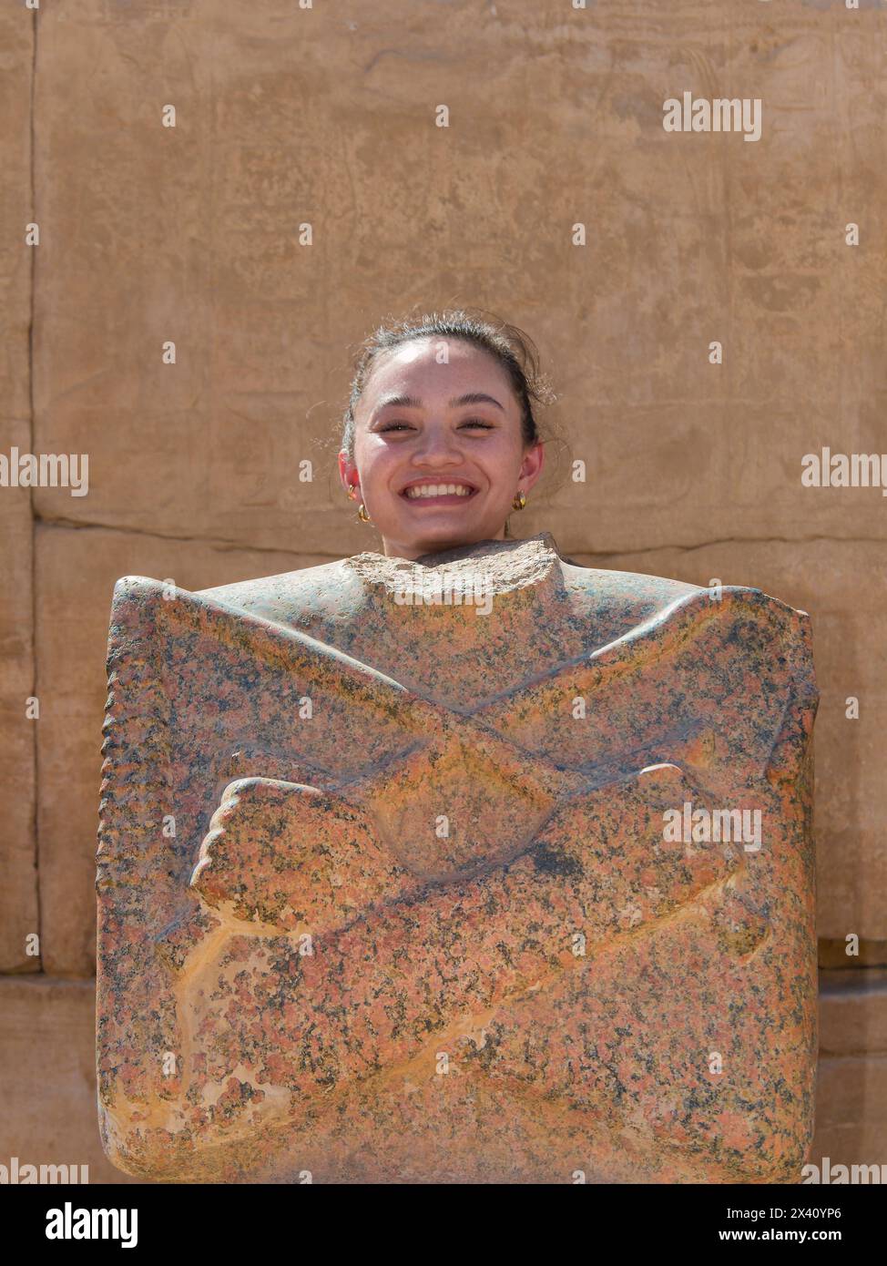 Girl posing as ancient Egyptian god with headless statue at the Karnak ...