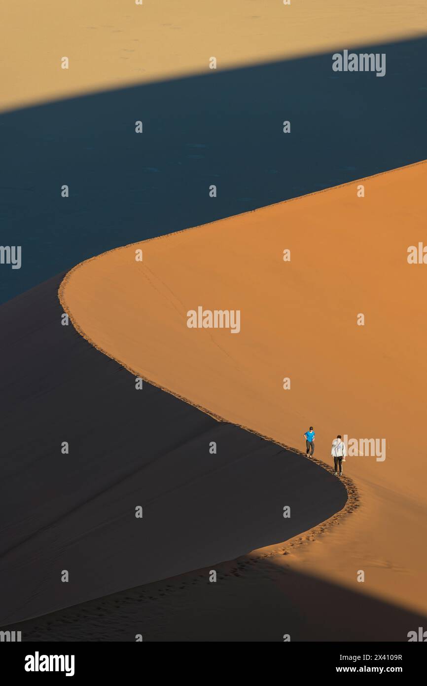 Couple climbing up Big Daddy dune at dawn in Namib-Naukluft Park ...