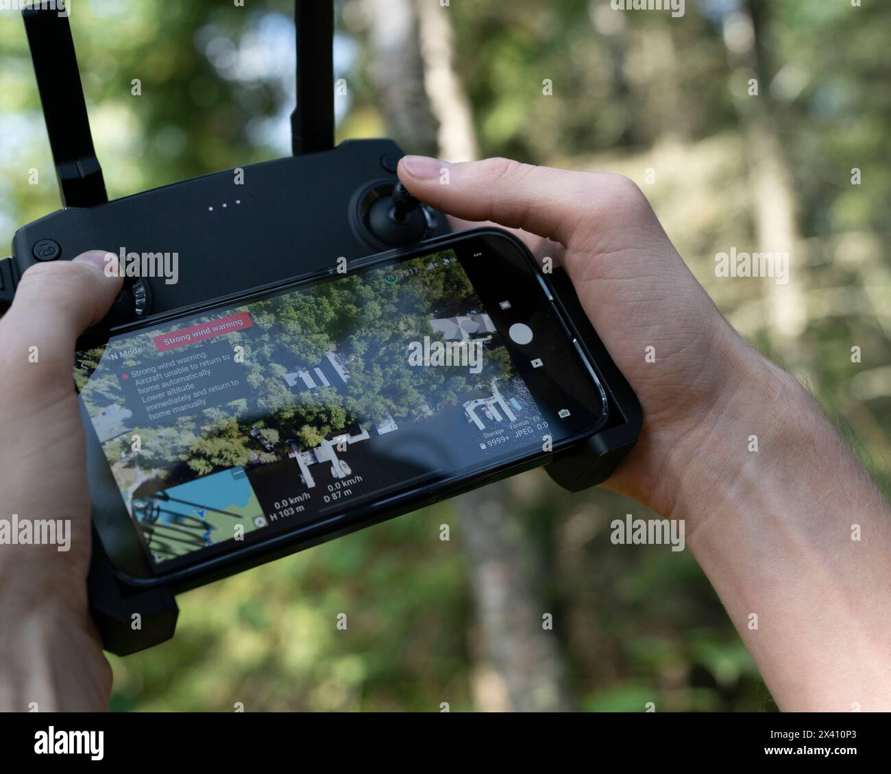 Hands holding a drone remote control with screen showing the aerial ...