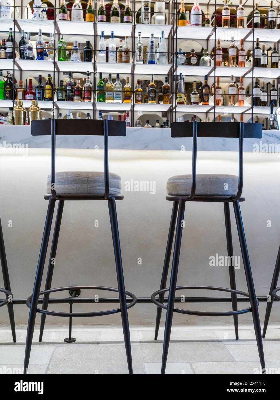 Bar stools and bottles of alcohol on display behind the bar; Greece ...