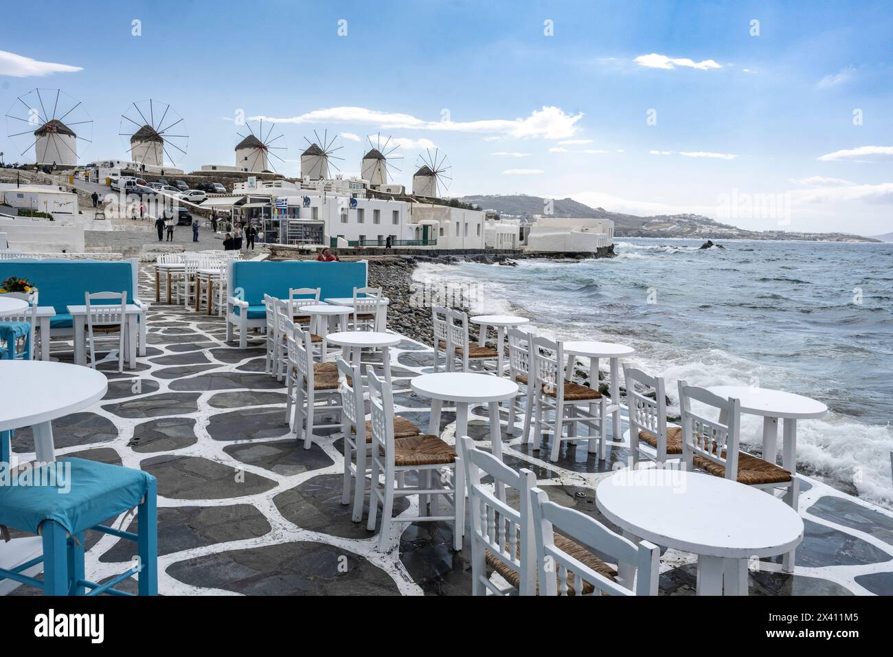 Tourists enjoy the waterfront of Mykonos, with a restaurant patio in ...