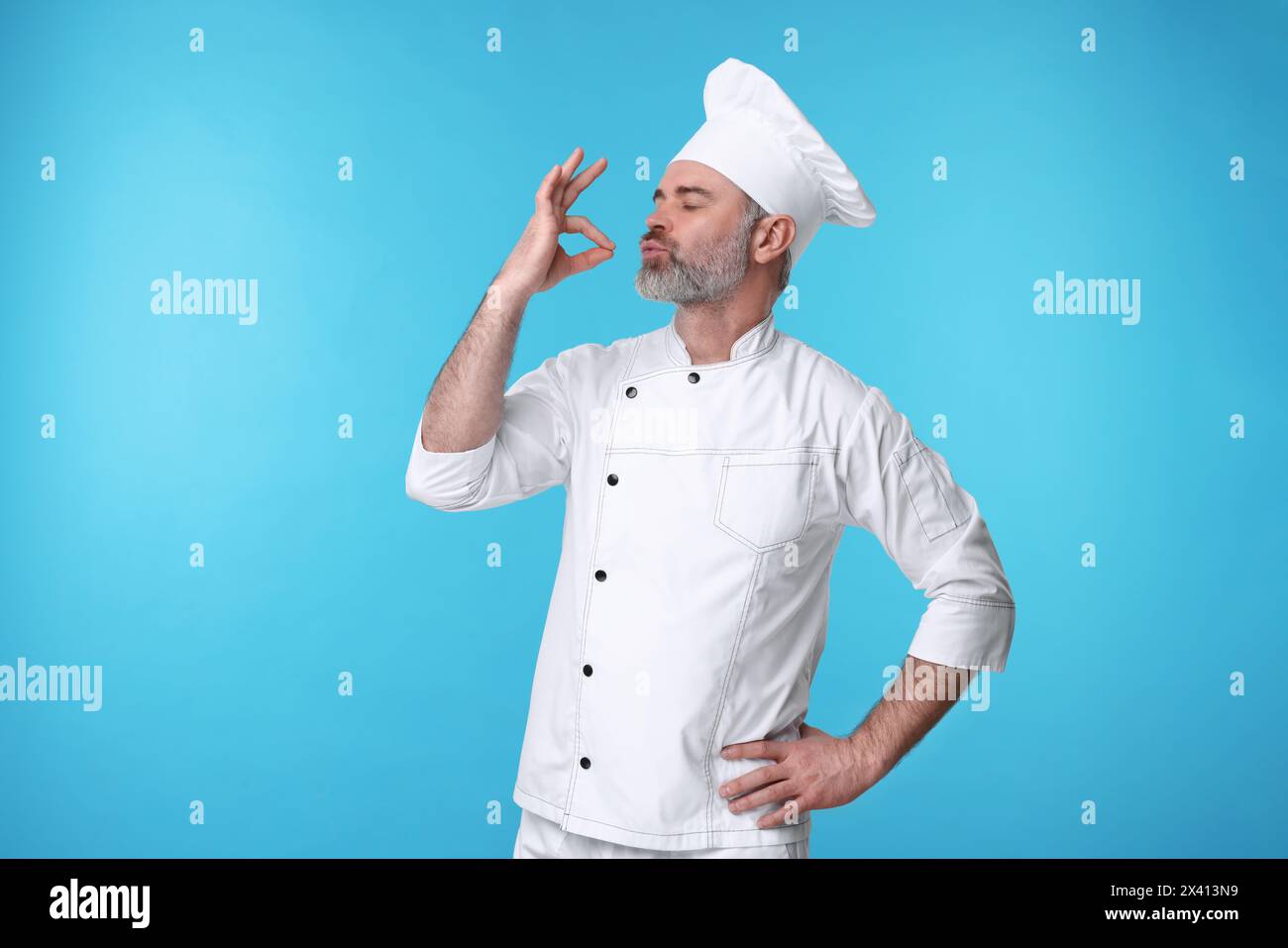 Chef in uniform showing perfect sign on light blue background Stock ...