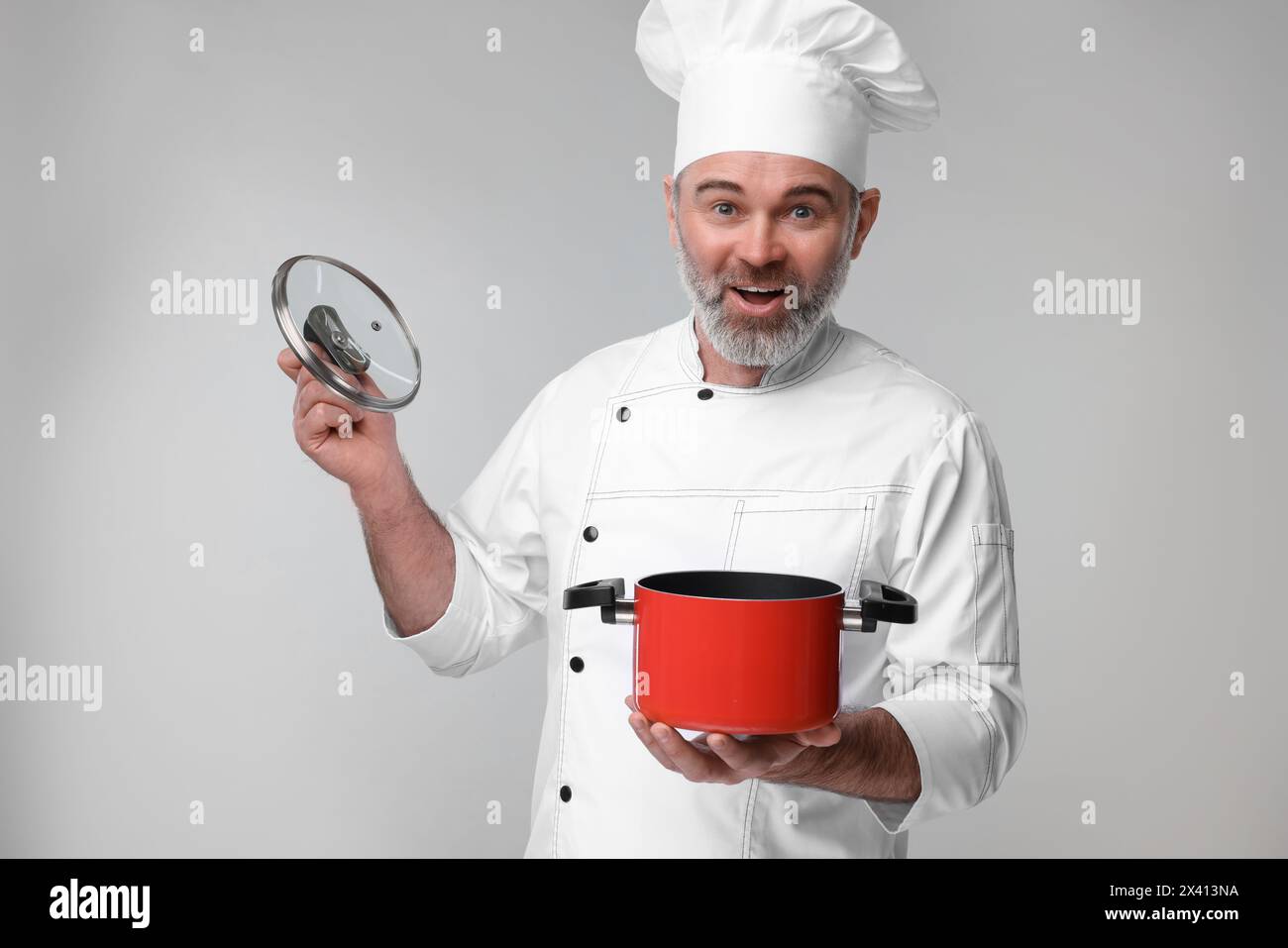 Surprised chef in uniform with cooking pot on grey background Stock ...