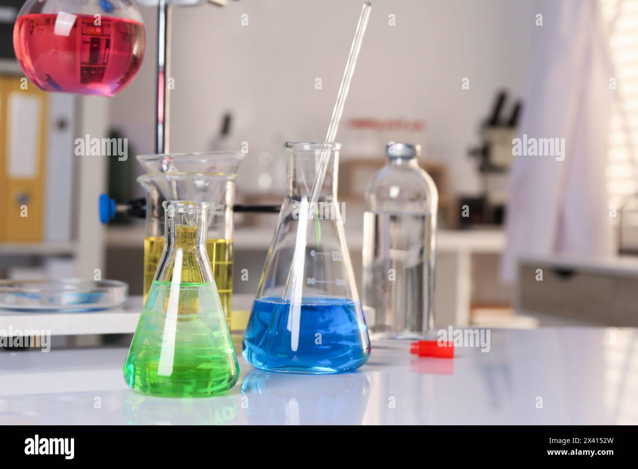 Laboratory analysis. Glassware with different liquids on white table ...