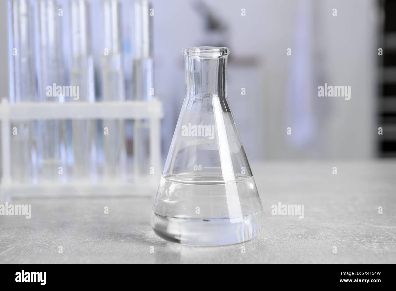 Laboratory analysis. Flask and test tubes on light grey table indoors ...