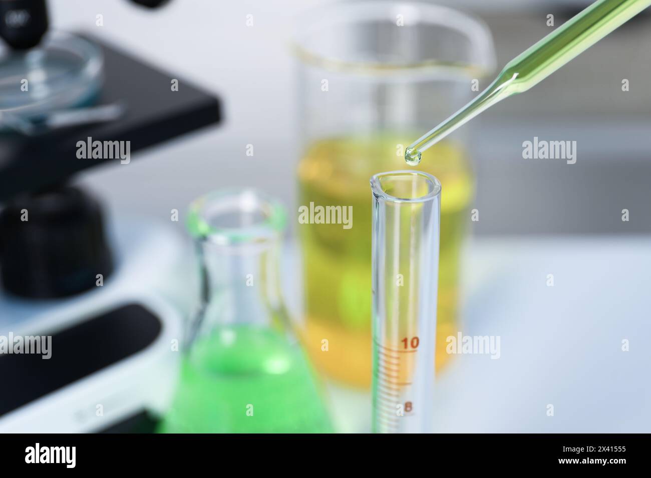 Laboratory analysis. Dripping liquid into test tube on table, closeup ...