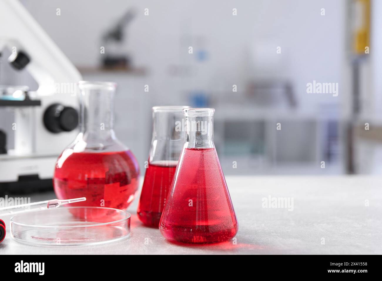 Laboratory analysis. Different flasks with red liquid and microscope on ...
