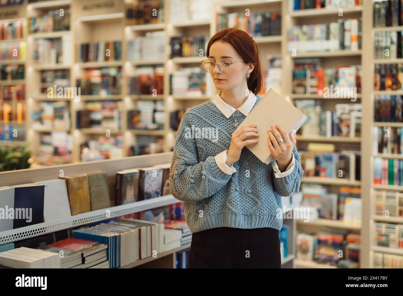 Woman in library holding a book Stock Photo - Alamy