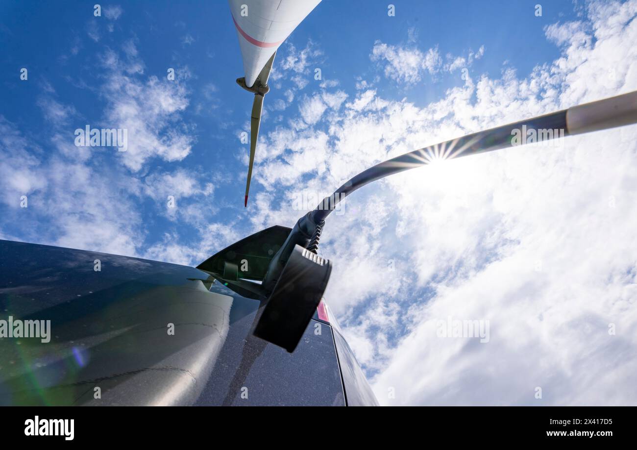 Wind turbine, technician charging his electric car during wind turbine ...