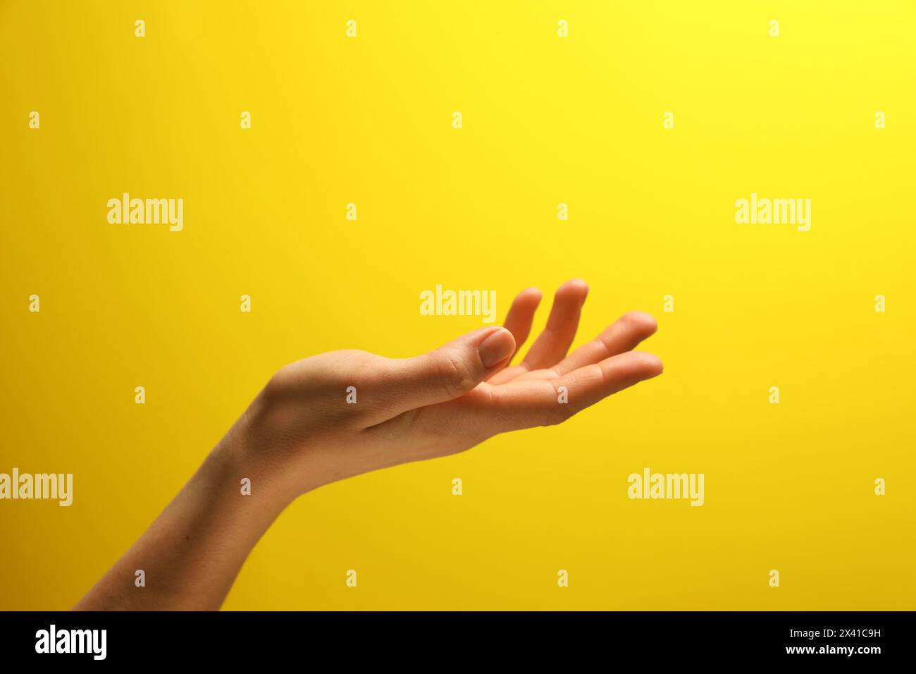 Woman holding something in hand on yellow background, closeup. Space ...