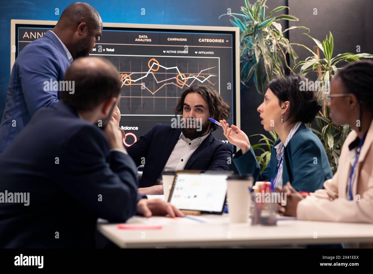 Teammates reviewing sales infographics on interactive board ...