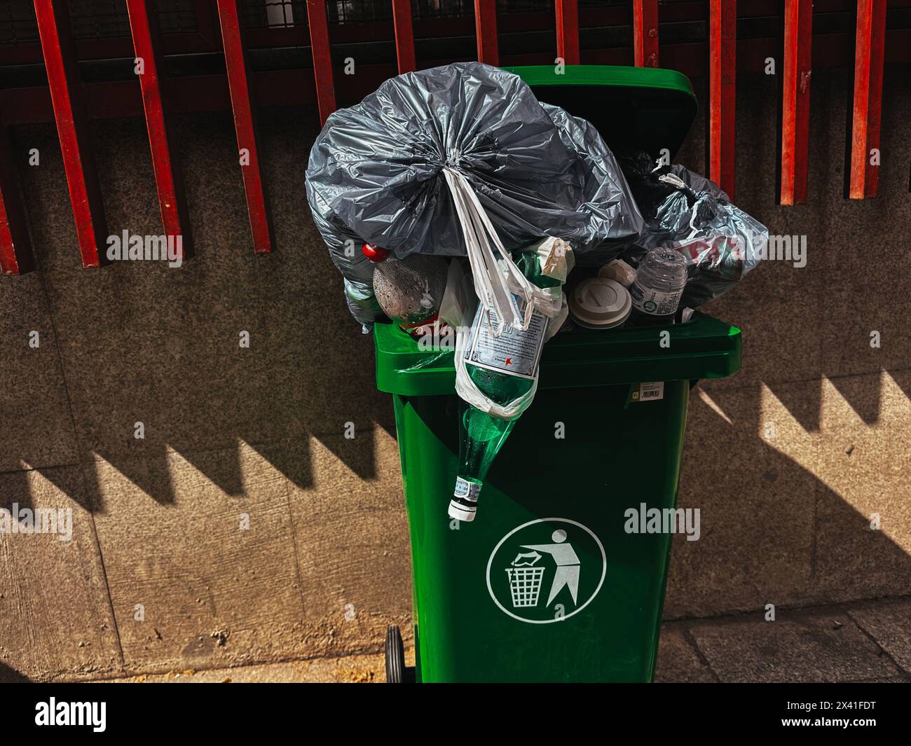 Madrid, Spain. April 29, 2024 Green garbage filled to the top with ...
