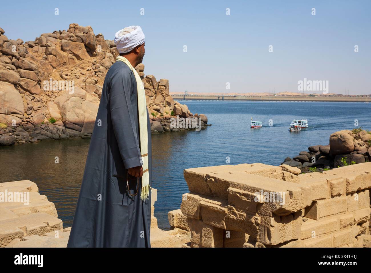 An Egyptian man in traditional attire looking at the Aswan Low Dam (Old ...
