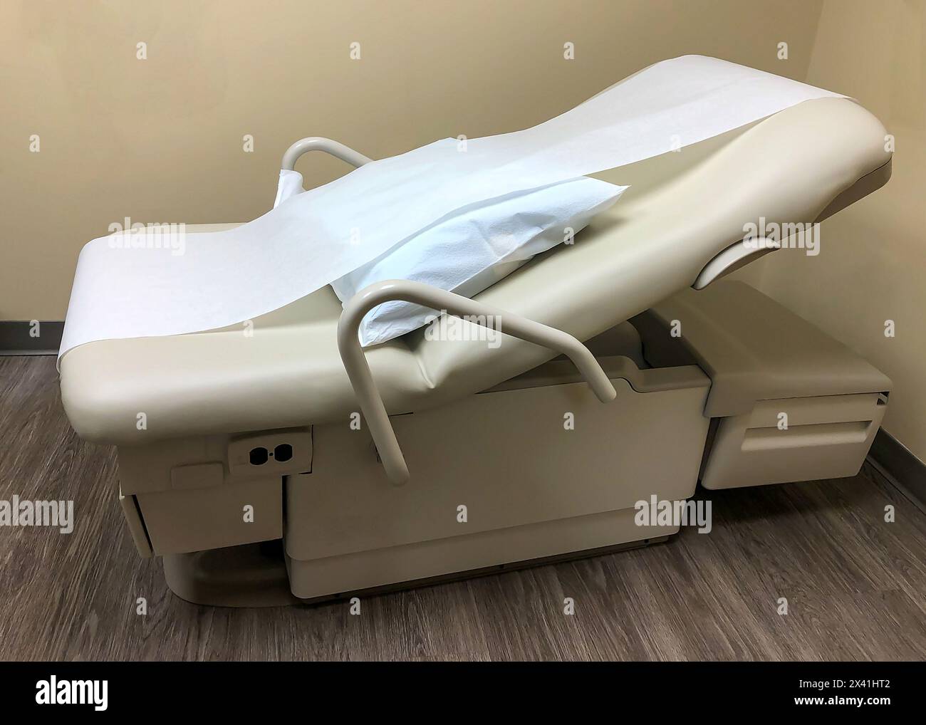 Medical exam table with disposable paper sheet and blue pillow cover in ...