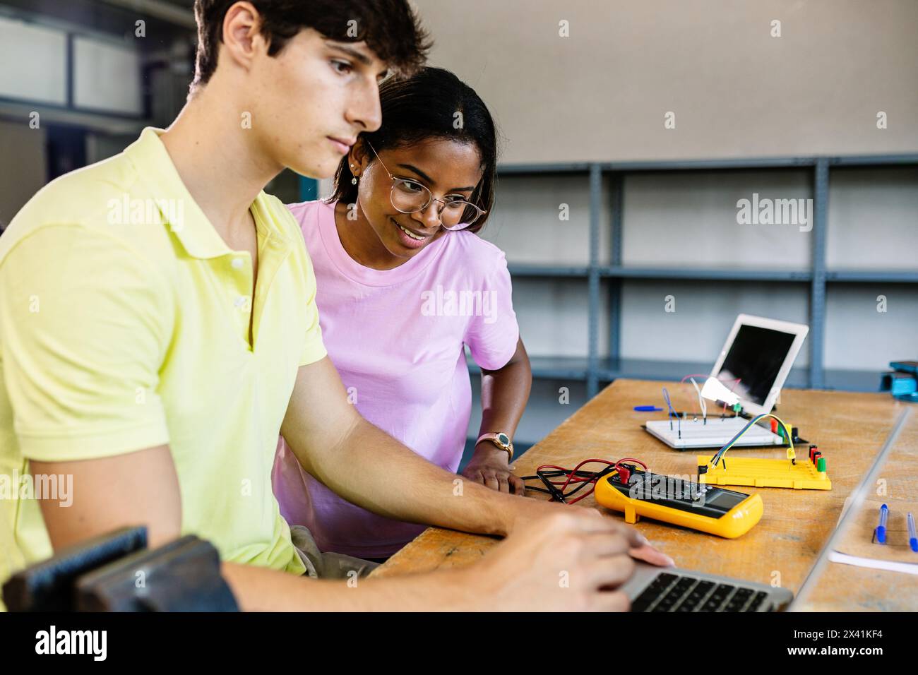 Two young high school students learning together at technology class ...