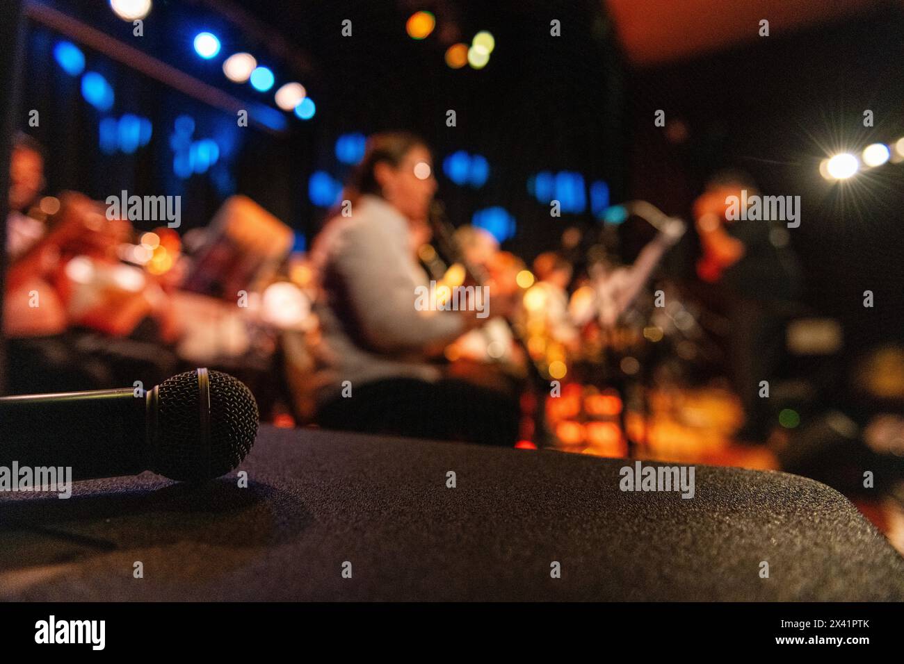 A microphone is on a table in front of a crowd. The crowd is blurry and ...