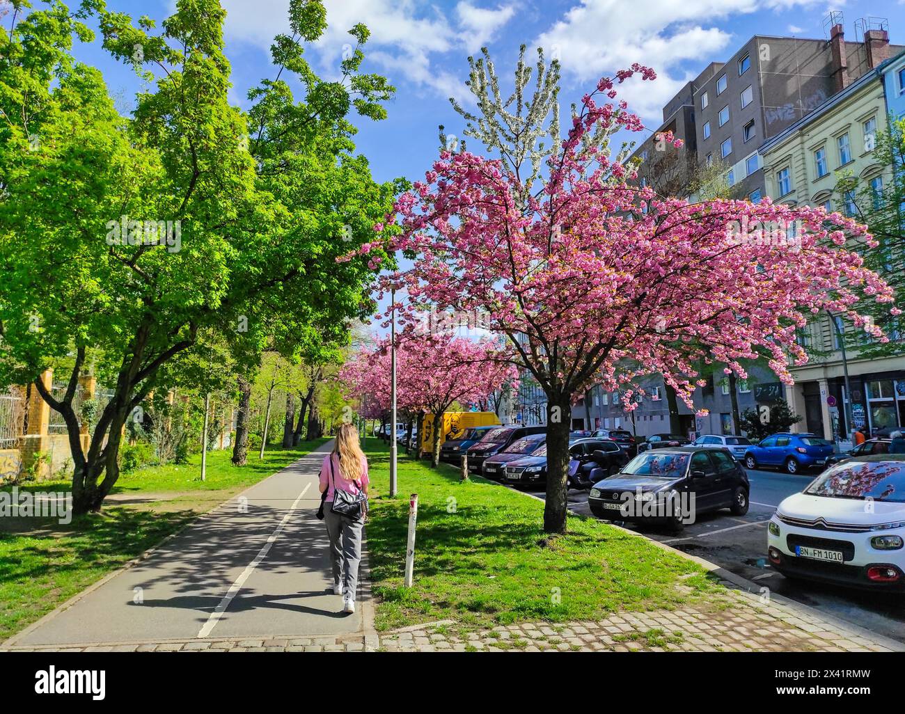 Unrecognisable woman in pink shirt walks along Wiener strasse in Berlin ...