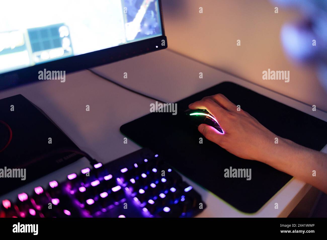 A person is playing a video game, his hand on his mouse. The lighting ...