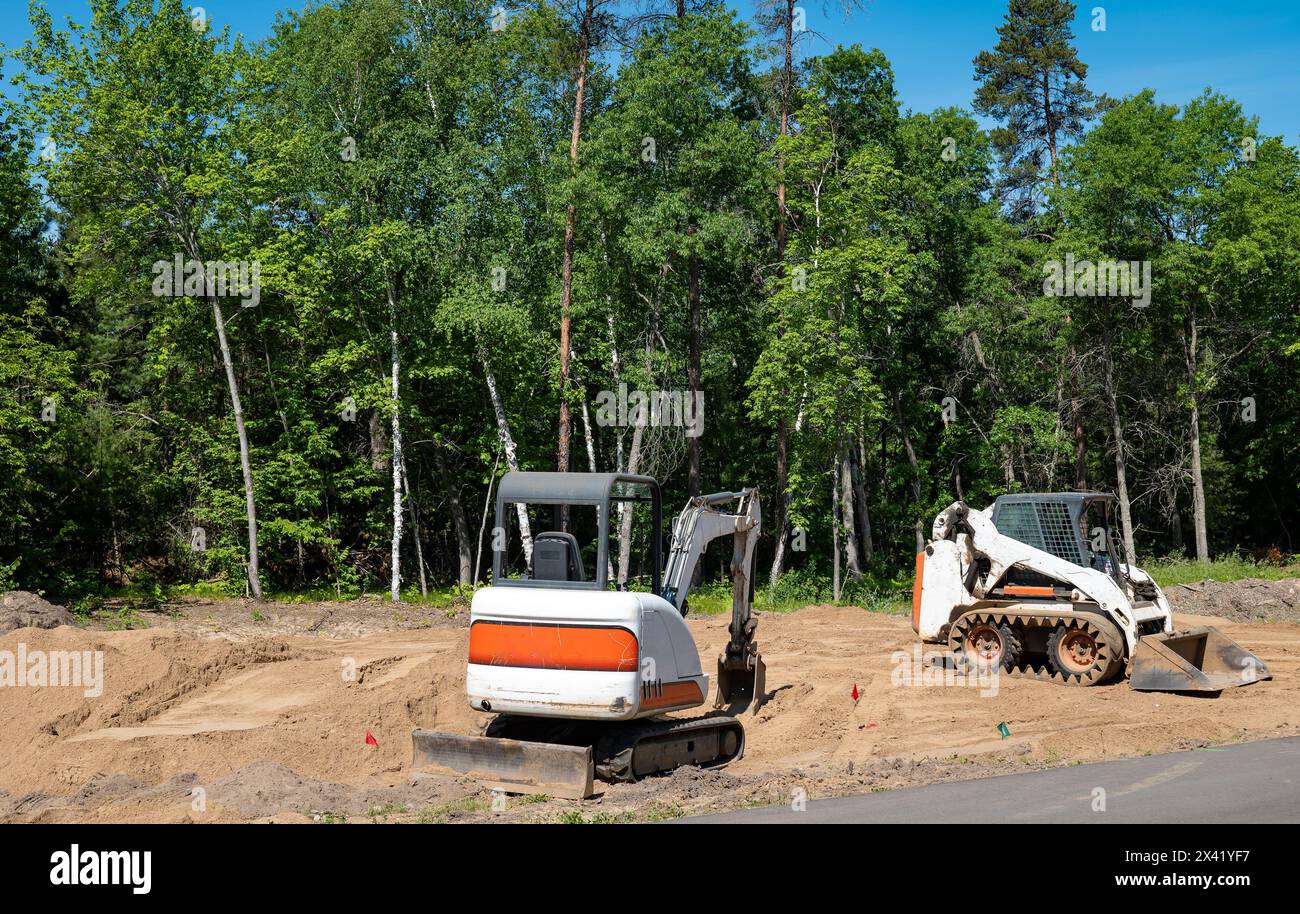 A compact front loader and mini excavator sits on the dirt at a new ...