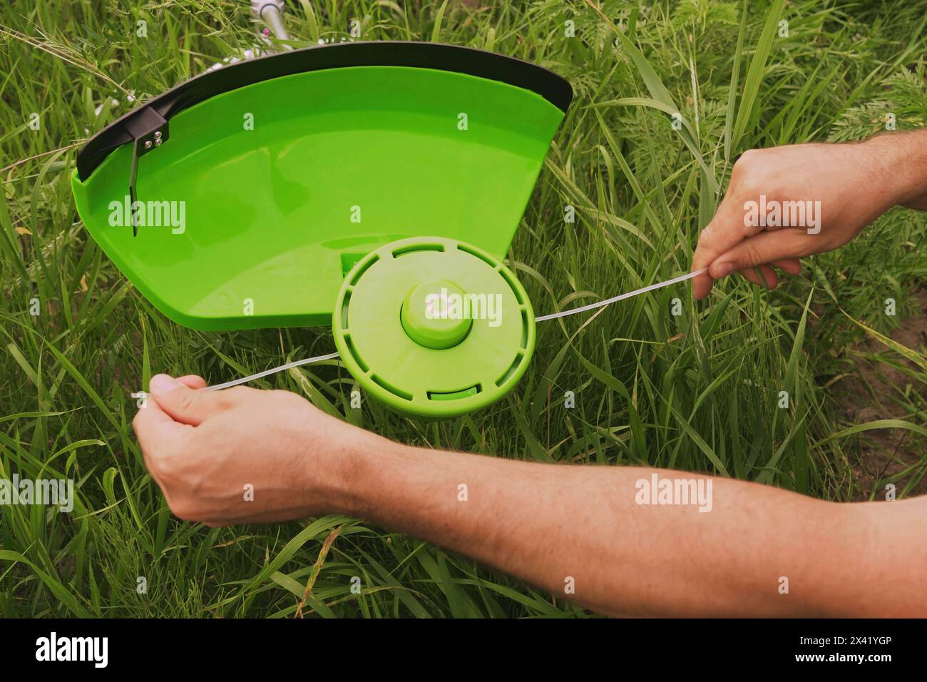 Servicing garden tools. Gardener worker attaches a reel to a mower in a ...