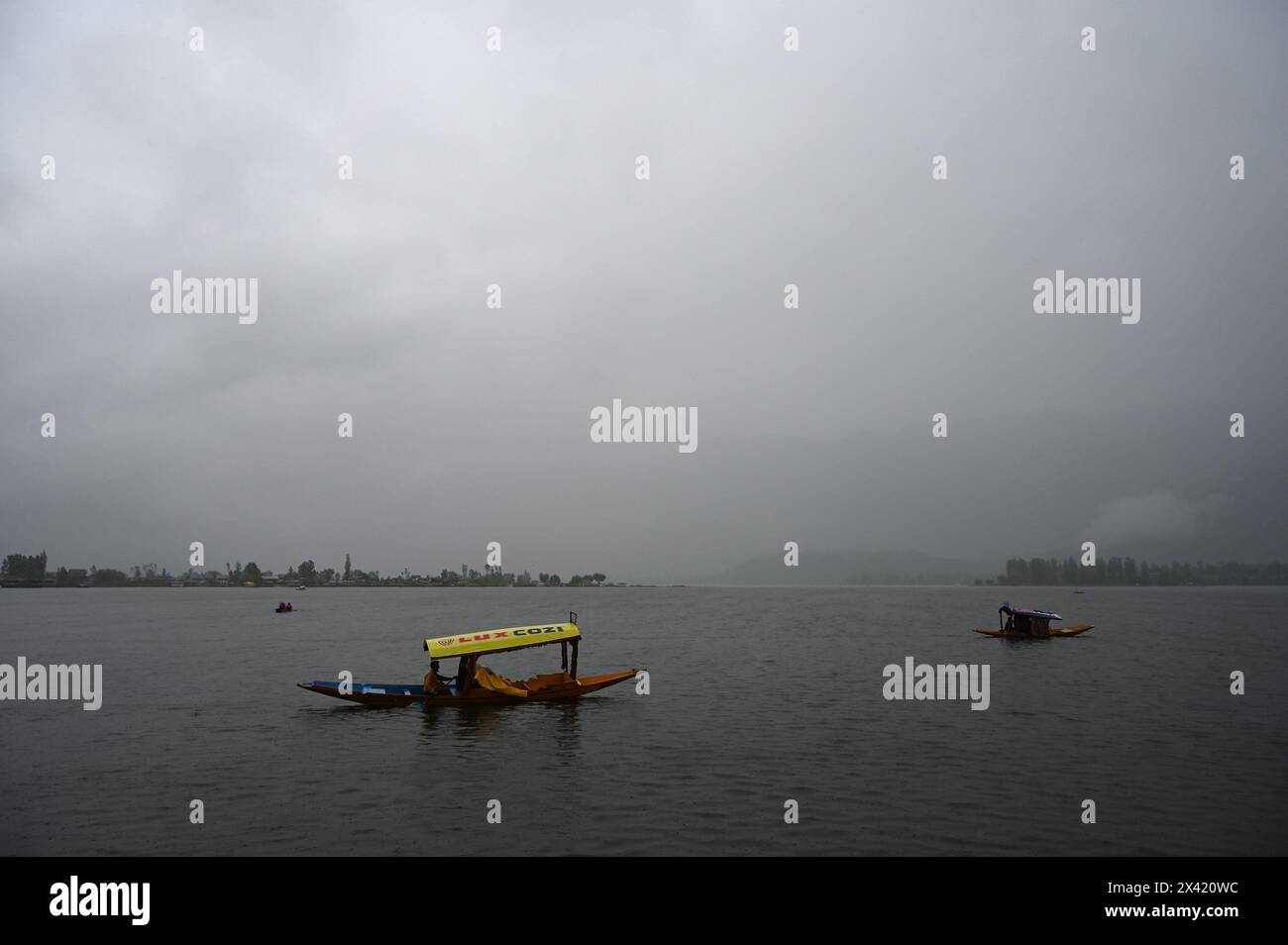 SRINAGAR, INDIA - APRIL 29: Boatmen row a boat during rain in Srinagar ...