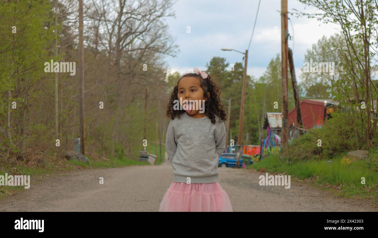 Portrait of girl standing on road against trees Stock Photo - Alamy