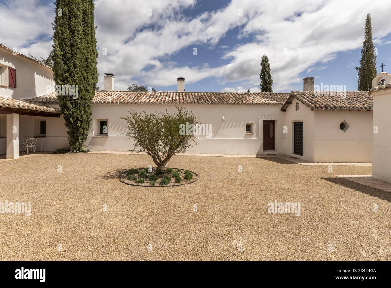 An Andalusian style patio in a farmhouse home with white facades and an ...
