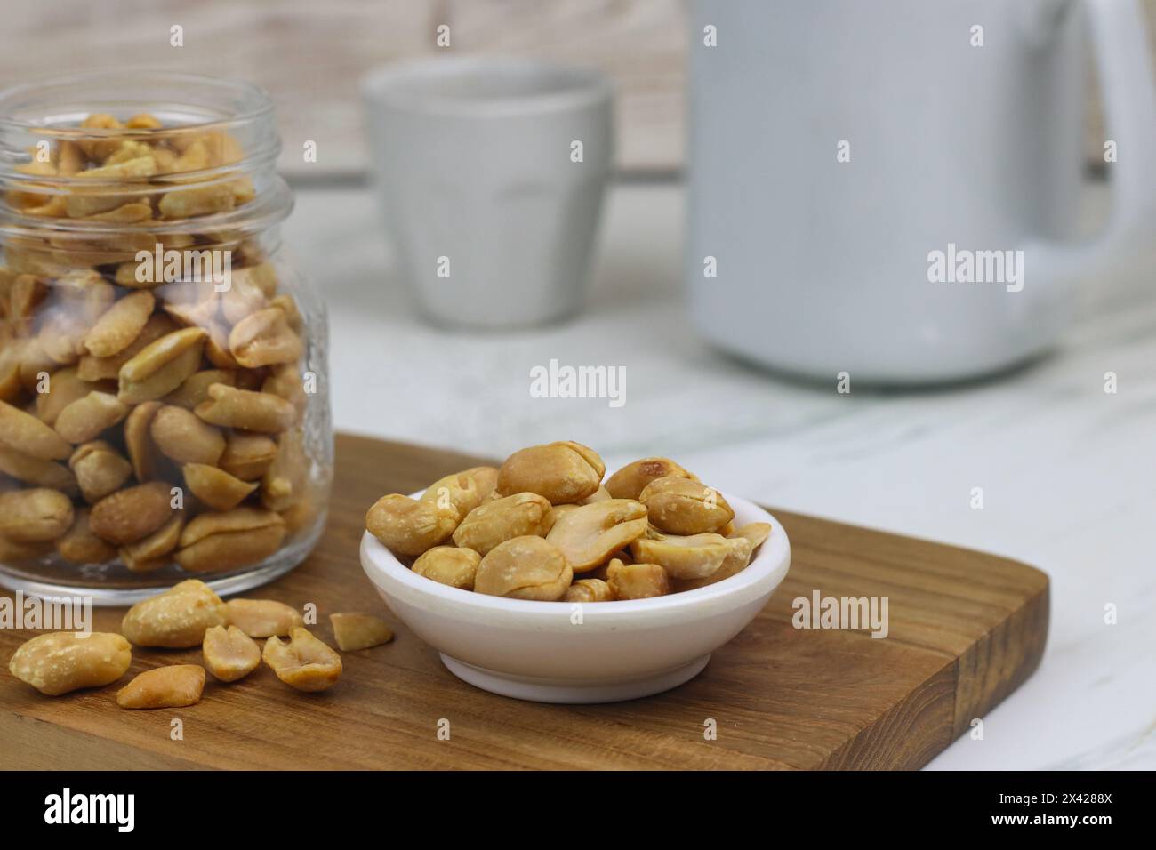 Kacang goreng or fried peanuts in a jar and white plate. Indonesian ...