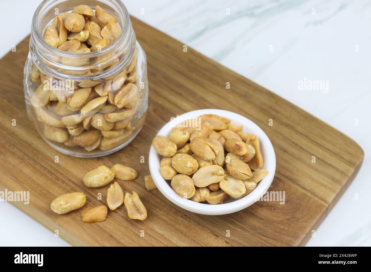 Kacang goreng or fried peanuts in a jar and white plate. Indonesian ...