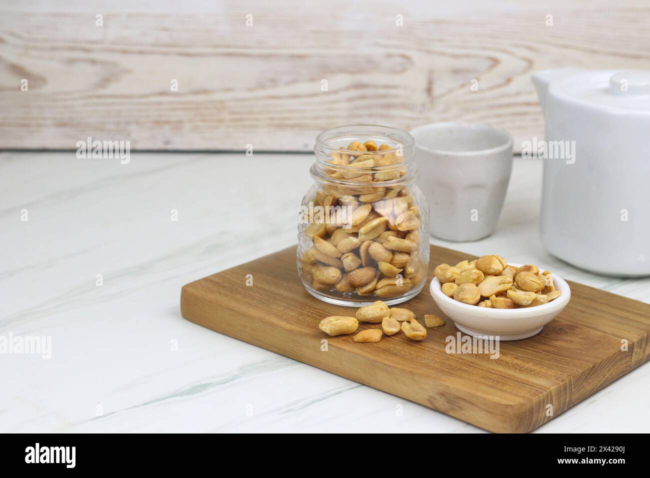 Kacang goreng or fried peanuts in a jar and white plate. Indonesian ...