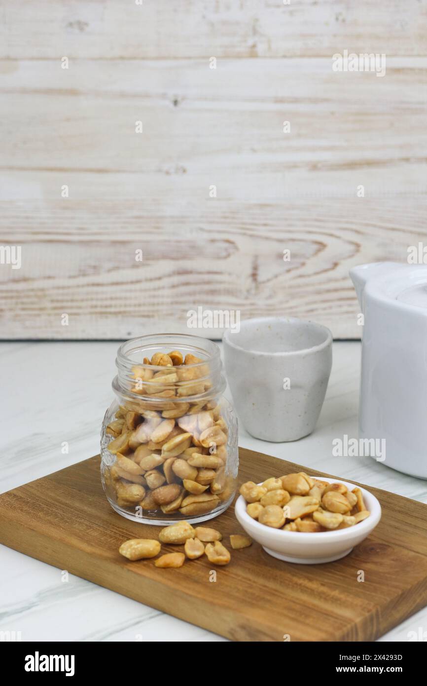 Kacang goreng or fried peanuts in a jar and white plate. Indonesian ...