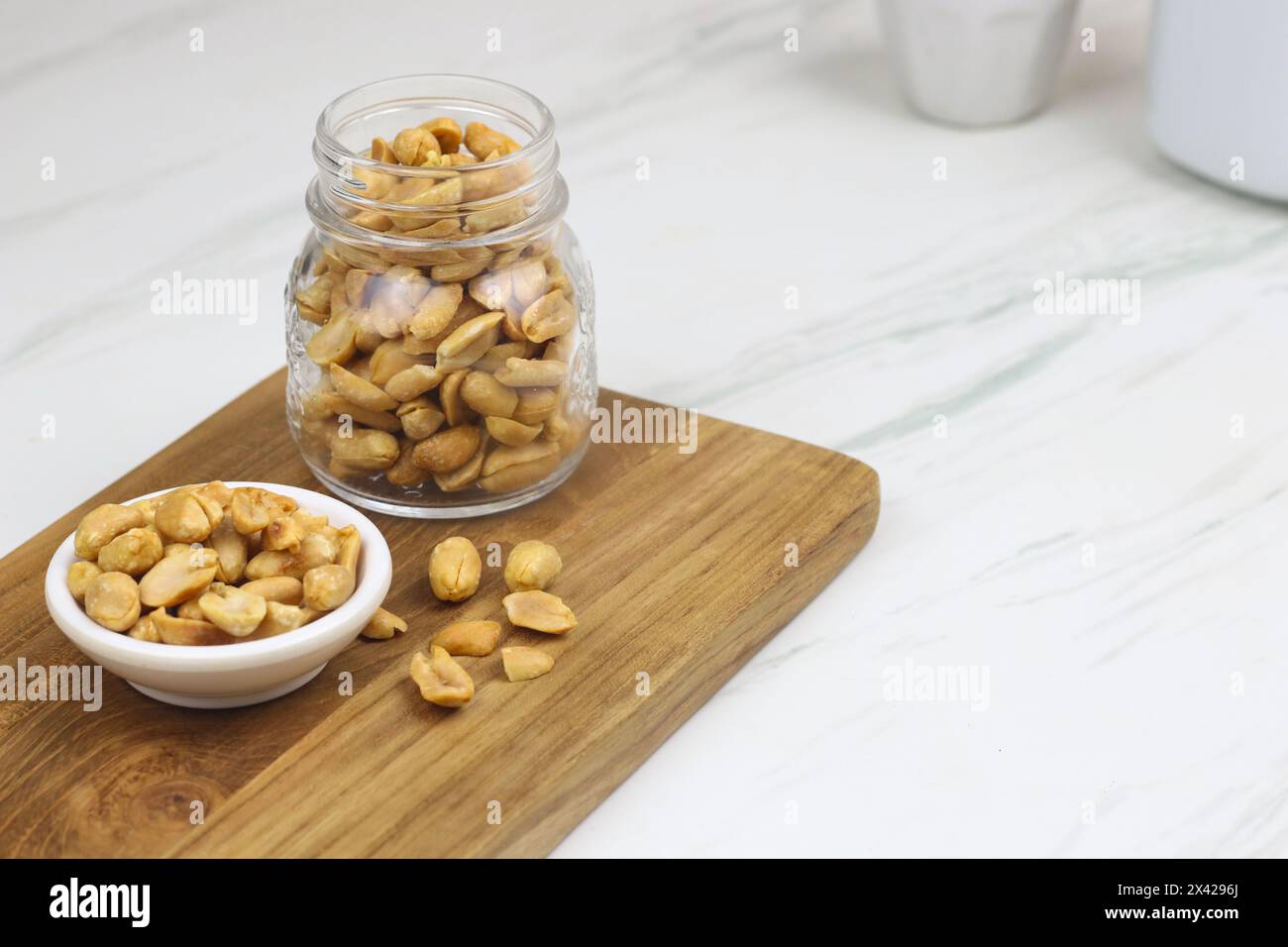 Kacang goreng or fried peanuts in a jar and white plate. Indonesian ...