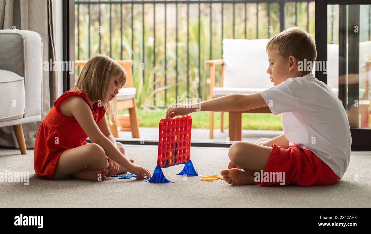 Siblings engrossed in a strategic board game, enhancing their logic ...