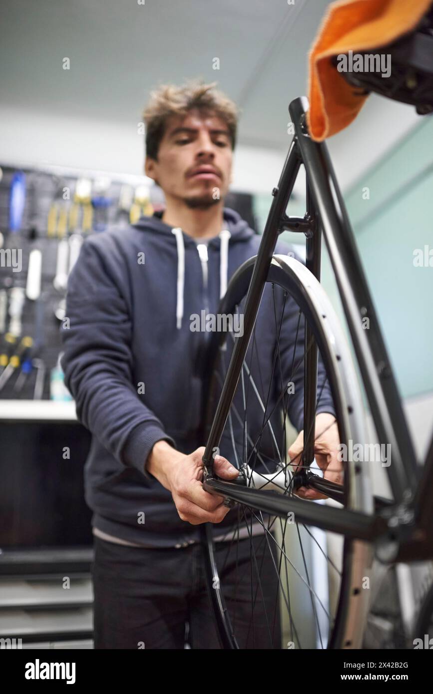 Hispanic bike technician evaluating the alignment of the rear wheel of ...