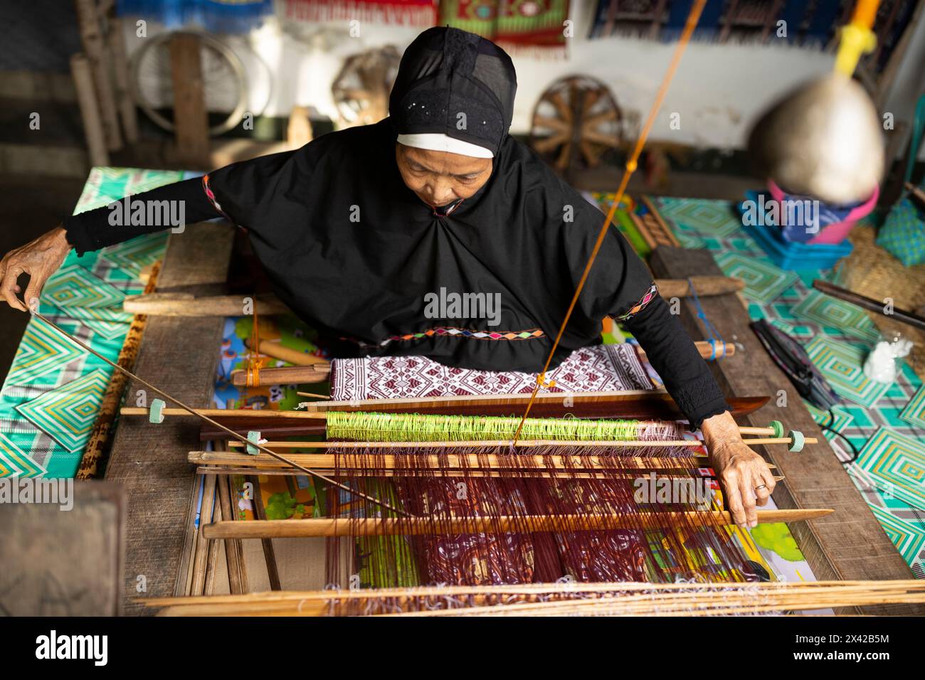 A village craftswoman weaving ikat fabric, Lombok, West Nusa Tenggara ...