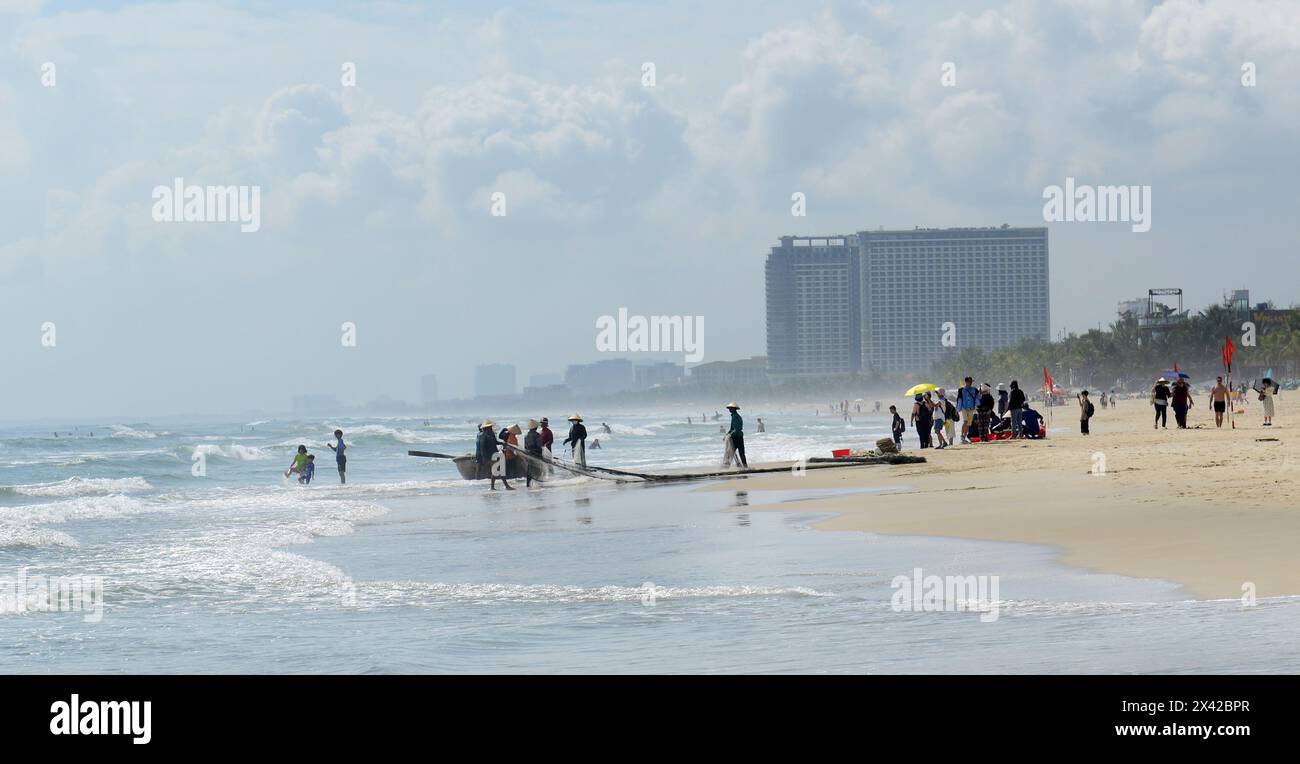 Vietnamese fishermen pulling out a large fishing net from the beach in ...