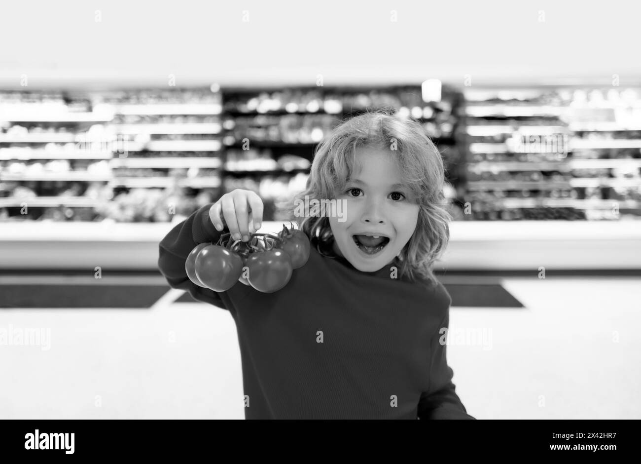 Child with fresh tomato vegetables. Kid choosing food in grocery store ...