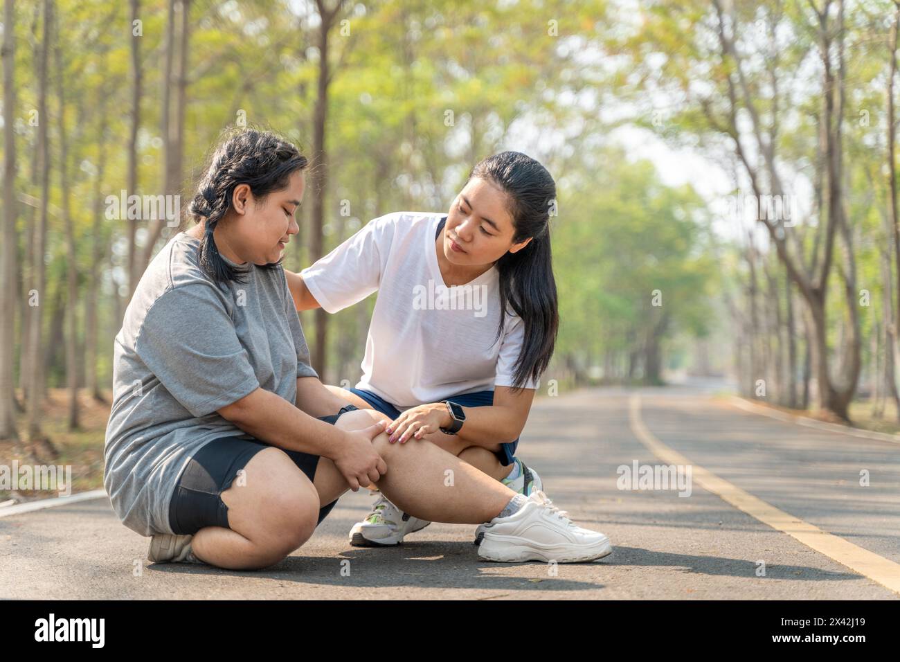 Overweight woman with knee injury sitting on the running track at a ...