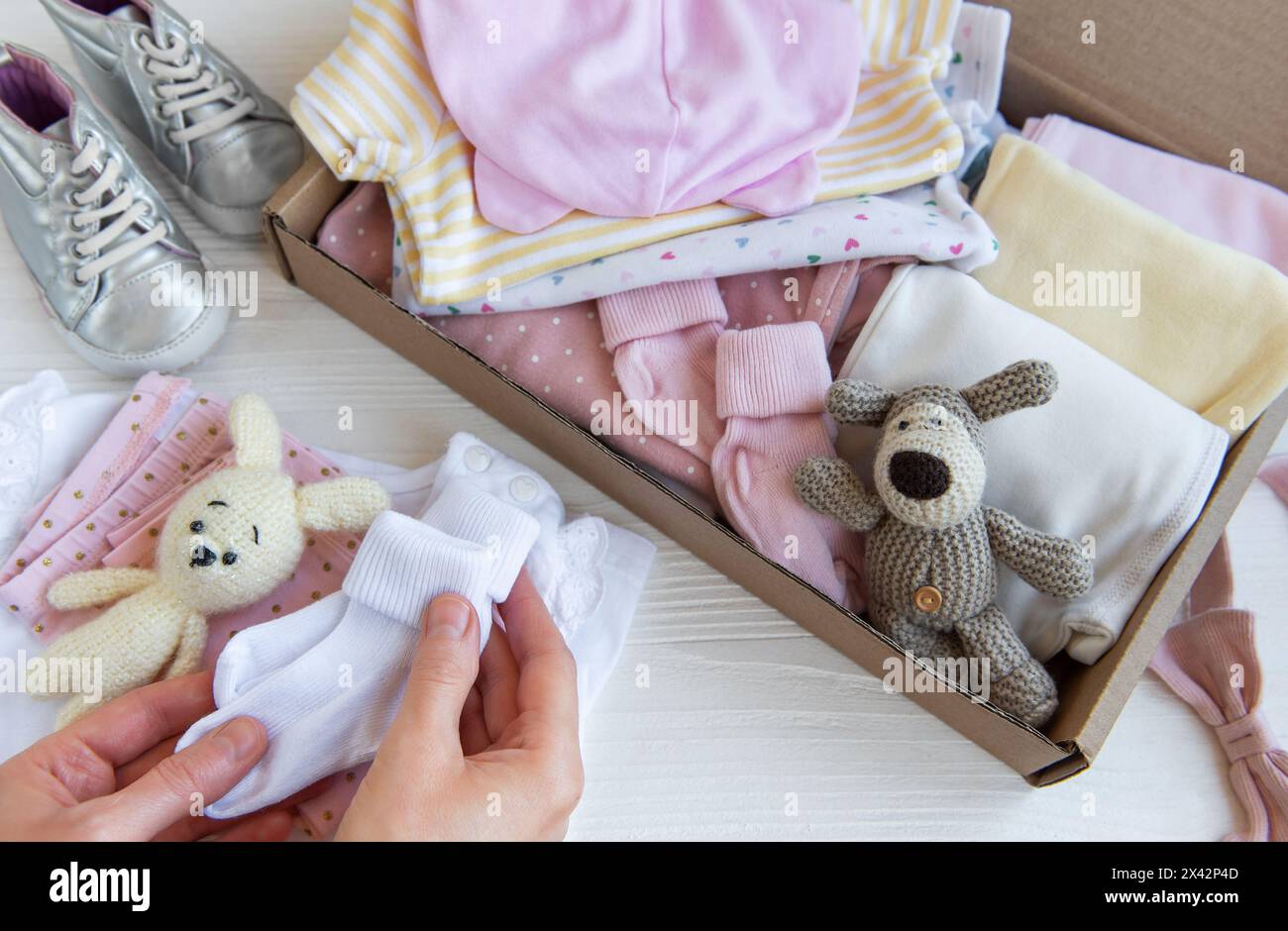 Women's hands collect children's clothes into boxes. The concept of ...