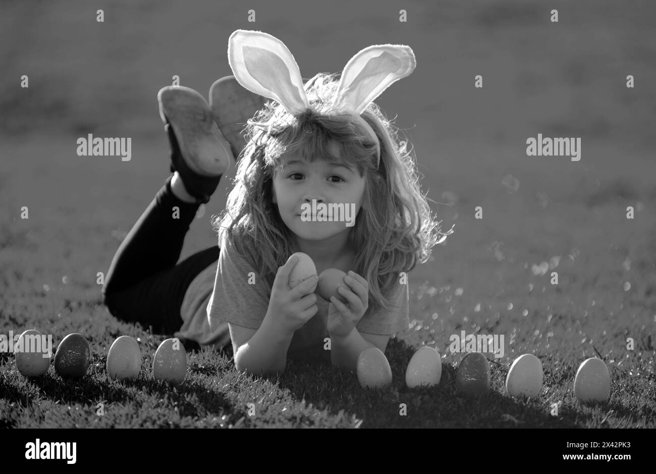 Easter bunny kids. Child boy with easter eggs and bunny ears on grass ...