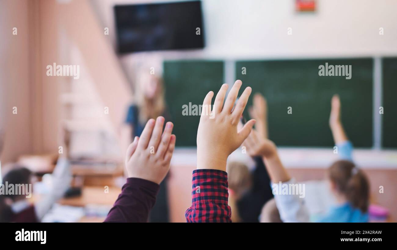Elementary school students raise their hands during class Stock Photo - Alamy