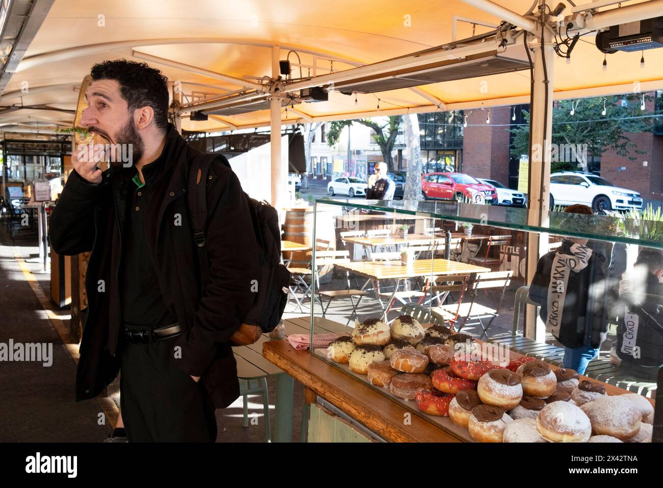 A young man eating a sandwich at a cafe in the South Melbourne Market ...