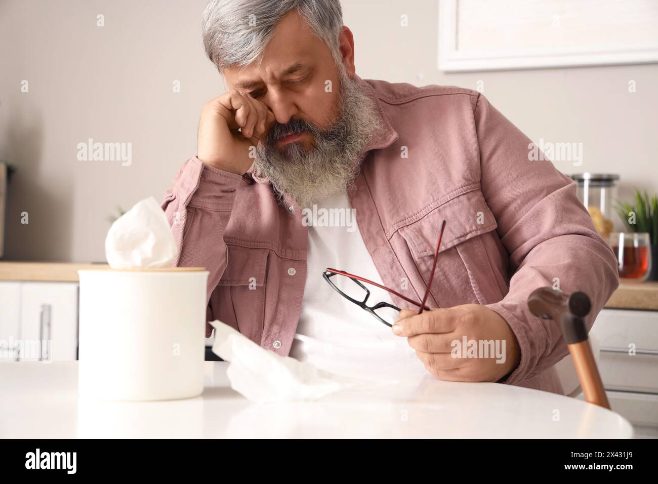 Portrait of sad senior man with tissues wiping eyes in kitchen Stock ...
