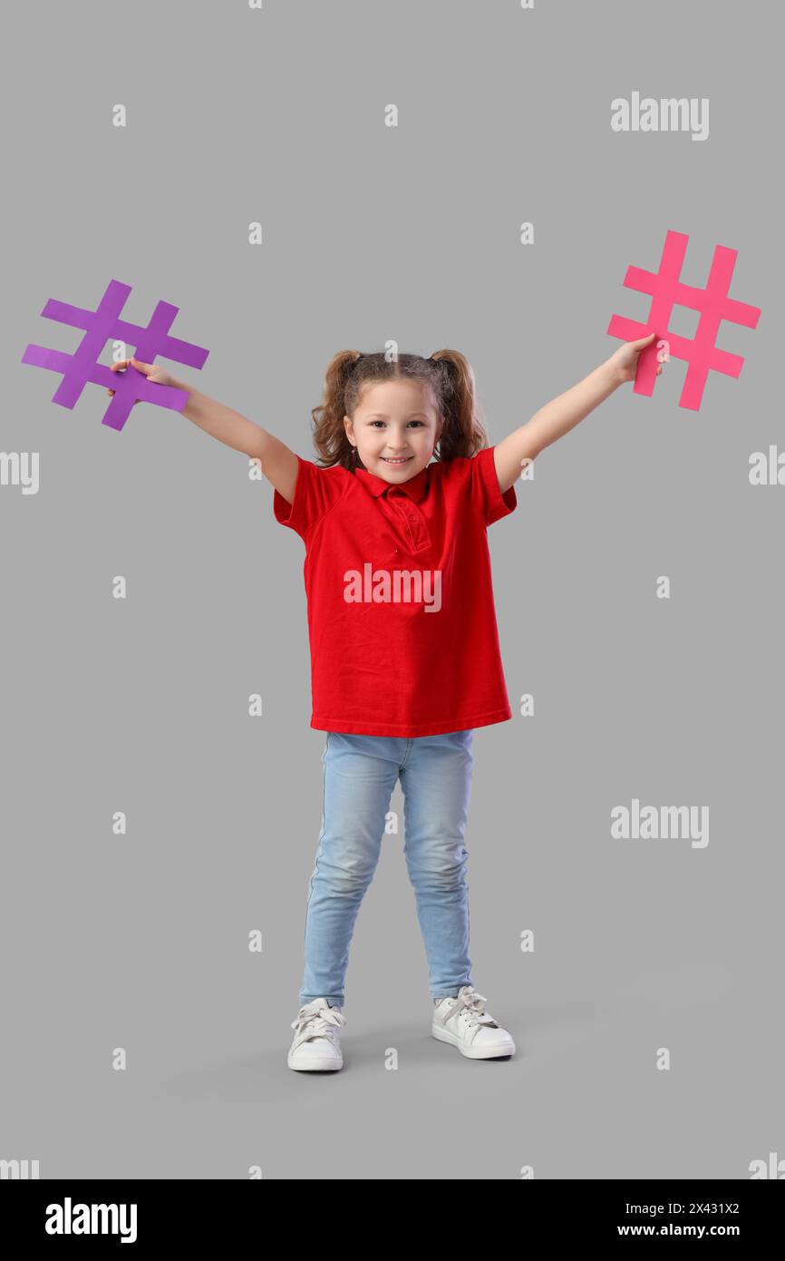 Cute little girl with hashtags on grey background Stock Photo - Alamy