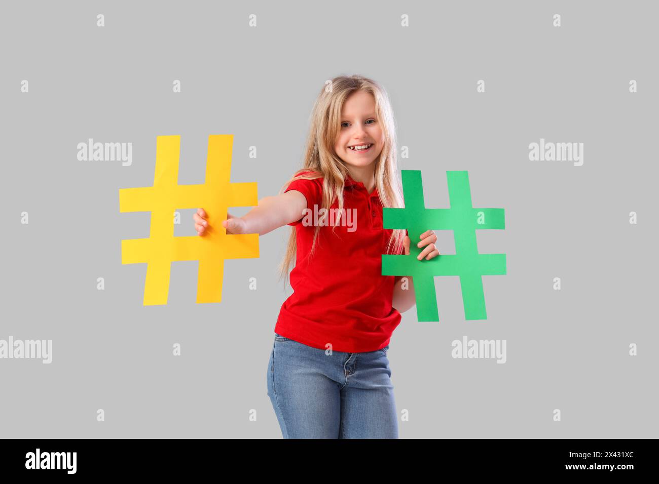Cute teenage girl with hashtags on grey background Stock Photo - Alamy
