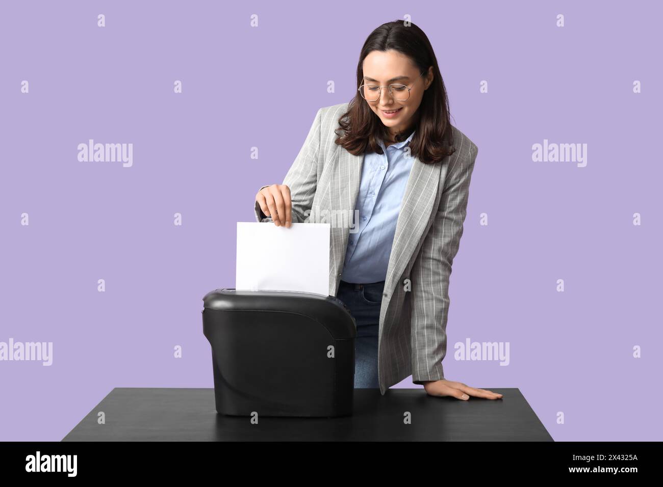 Secretary destroying document in shredder on lilac background Stock ...